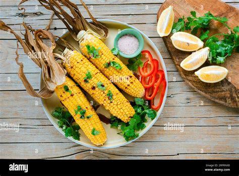 baked corn cobs with coriander sliced bell pepper lemon and salt on