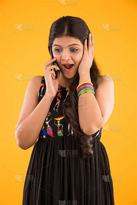 聪明的印度女孩在黄色背景下使用智能手机