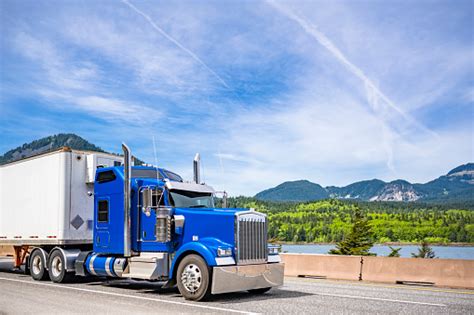 컬럼비아 강을 따라 고속도로를 달리는 냉장 세미 트레일러로화물을 운송하는 크롬 부품이 있는 밝은 파란색 클래식 빅 리그 세미 트럭 트랙터 0명에 대한 스톡 사진 및 기타