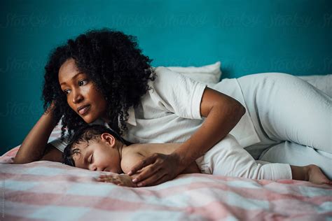Mother Lying On Bed With Sleeping Baby By Stocksy Contributor Atolas Stocksy