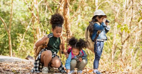 다양성의 그룹 여름 화창한 날에 숲 산에서 함께 배낭 하이킹을 하는 어린 소녀 친구들 세 아이가 앉아서 숲을 탐험하는 지도를 보며 즐거운 야외 활동을 하고 있습니다 사진