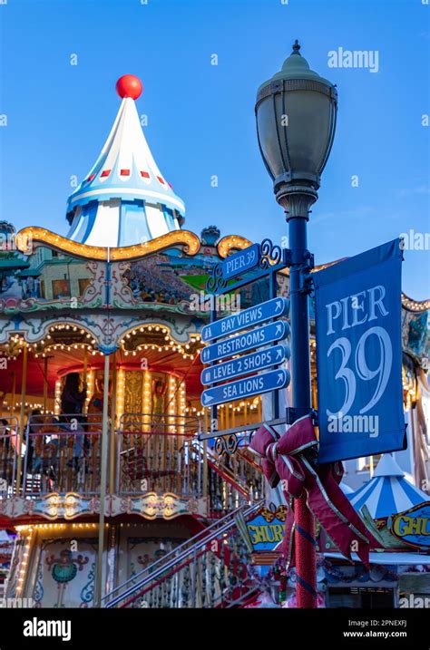A Picture Of The Signs Of Pier 39 Next To Its Iconic Colorful Carousel
