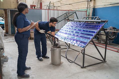 태양 전지 패널 공장에서 테스트를 위해 패널에 물을 펌핑하는 근로자를 감독하는 흑인 여성 감독자 2명에 대한 스톡 사진 및 기타