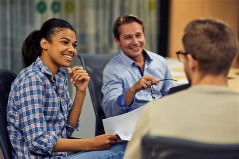 젊은 쾌활한 혼합 인종 여성 사무원이 동료와 사업을 논의하면서 공동 작업 공간이나 현대적인 사무실에서 책상에 앉아 18 19세에 대한 스톡 사진 및 기타 이미지 Istock