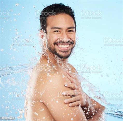 초상화 물 샤워는 위생이나 수분 공급을 위해 파란색 배경에 스튜디오에 있는 남자 모델과 함께 합니다 얼굴 아름다움 및 스킨 케어 잘 생긴 젊은 남성이 욕실에서 물 튀김에