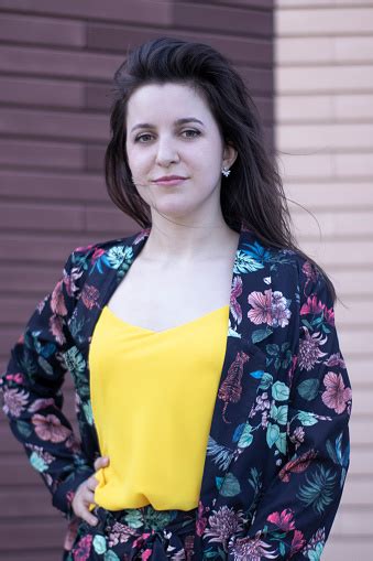 매력적인 젊은 갈색 머리 여자 에 노란색 티셔츠와 꽃 반바지 의상 갈색 벽 배경 복사 공간을 복사합니다 20 29세에 대한 스톡