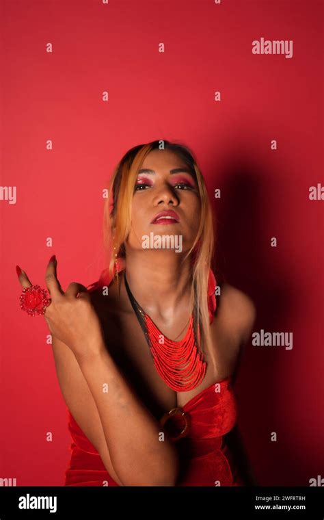 Stunning Woman In Vibrant Red Attire Striking A Pose Against A Complementary Red Backdrop