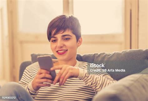 스마트 전화 얘기 하 고 인터넷 및 소셜 미디어 기술 라이프 스타일 통신 및 사람들 개념에 집에서 소파에 앉아 메시지 확인에 행복 꽤 젊은 백인 여자 가정 생활에 대한 스톡