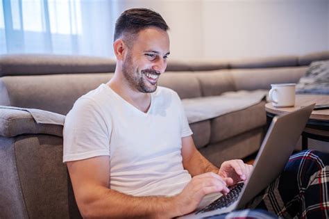 무릎과 입력에 노트북과 거실에서 바닥에 앉아 잠옷에 잘 생긴 미소 백인 남자 가정용 장비에 대한 스톡 사진 및 기타 이미지 가정용 장비 가정의 방 거실 Istock