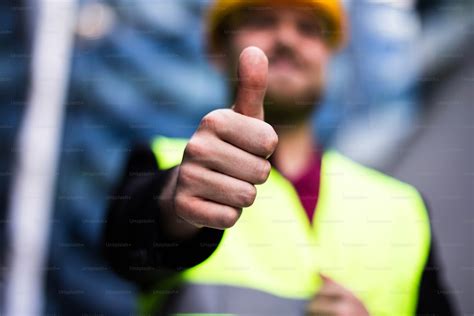 거리에 서 있는 웃는 엔지니어 클로 업 엄지 손가락 사진 Unsplash의 바깥 이미지