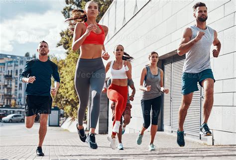 Full Length Of People In Sports Clothing Jogging While Exercising On