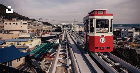 빨간색과 흰색이 섞인 기차가 선로를 따라 달리는 모습 사진 Unsplash의 무료 부산 이미지