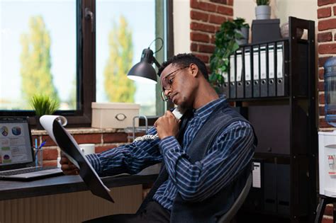 기울어진 머리 음소거 대화로 어깨에 전화 수신자를 들고 있는 스타트업 직원 벽에 대한 스톡 사진 및 기타 이미지 벽 사람들 사무실 Istock