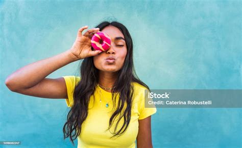 파란색 배경에 도넛으로 눈을 가리는 젊은 여성의 초상화 카메라에 키스를 하는 아시아 아프리카의 행복한 소녀 가리기에 대한 스톡 사진 및 기타 이미지 Istock