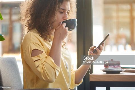 곱슬 소녀 카페에서 마시는 커피를 편안 하 게 스마트폰을 사용 하 여 경기 스포츠에 대한 스톡 사진 및 기타 이미지 경기 스포츠 고객 고름 Istock