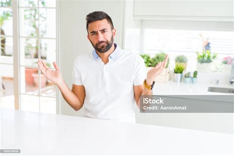 잘 생긴 히스패닉 남자 캐주얼 흰색 티셔츠 집에서 단서와 팔과 손을 제기 와 혼란 표정 의심 개념 T 셔츠에 대한 스톡 사진 및 기타 이미지 Istock