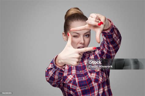 빨간색 분홍색 체크 무늬 셔츠에 아름 다운 금발 여자 수집 롤빵 헤어스타일 메이크업 위와 구성 제스처를 자르기 카메라를 보고