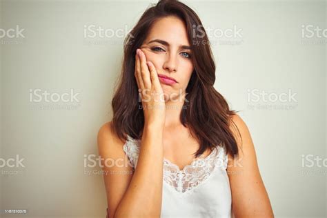 피곤하고 교차 팔우울증 문제로 지루 해 보이는 흰색 고립 된 배경 위에 서 있는 티셔츠를 입은 젊은 아름다운 여성 T 셔츠에