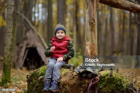 가을 날 숲에서 하이킹 하는 동안 작은 보이 스카우트 아이는 뜨거운 차를 마시고 샌드비치를 먹고 있다 아이 뒤에는 티피 오두막이 있습니다 아이에 대한 스톡 사진 및 기타
