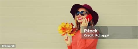 회색 배경에 모자를 쓰고 스마트 폰을 부르는 노란색 단풍 나무 잎을 가진 행복한 미소 짓는 젊은 여성의 가을 초상화 20 29세에 대한 스톡 사진 및 기타 이미지 Istock