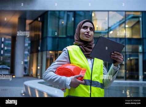 Uk London Female Engineer In Hijab Holding Tablet On Front Of Modern