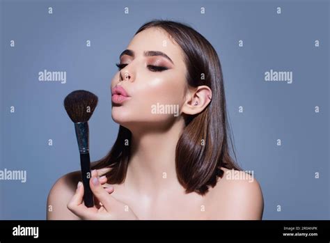 Studio Portrait Of A Woman Applying Cosmetic Tonal Foundation On Face