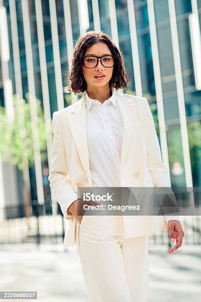 정장 한 흰색 양복을 입고 안경을 쓴 자신감 넘치는 사업가가 대낮에 현대적인 도시 풍경 속에서 야외를 걷고 있습니다 20 24세에 대한 스톡 사진 및 기타 이미지 Istock
