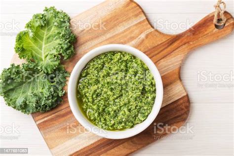 페스토 소스 케일 곱슬 양배추 올리브 오일 잣 음식 마늘 녹색 나무 배경 테이블 빛 요리 채식 점심 신선한 미식가 닫다 건강 한 집에서 만든 부엌 비건 채식 먹는 보드