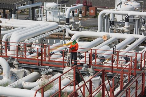 육안 검사 기록 파이프라인 오일의 정유 밸브 동안 스테이션 오일 공장의 강철 긴 파이프 및 파이프 엘보 밸브에서 남성 작업자 검사 프리미엄 사진