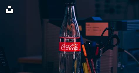 안경 근처에 빈 코카콜라 병 프린터 용지 키보드 흰색 테이블 위의 컴퓨터 마우스가 있습니다 사진 Unsplash의 무료 미국 이미지