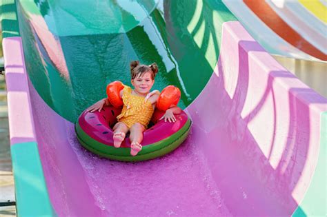 아쿠아 파크에서 워터 슬라이드를 타고 있는 어린 미취학 소녀 열대 휴양지에서 가족 여름 방학을 즐기며 즐거운 시간을 보내는 행복한 아이 어린 아이와 아기를 위한 젖은