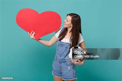 예쁜 젊은 여자 축구 팬 응원 축구 공 파란색 청록색 배경에 고립 빈 빈 붉은 마음으로 좋아하는 팀 지원 사람들의 감정 스포츠 가족 레저 라이프 스타일 개념입니다 갈색