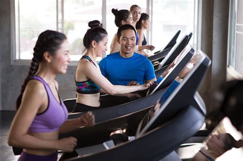 스포츠 체육관에서 디딜 방 아에서 실행 하는 젊은 사람들의 그룹입니다 아침 시간에 트레이너 남자와 함께 실행 하는 기계에 피트 니스 여자 주자 건강한 생활방식에 대한 스톡