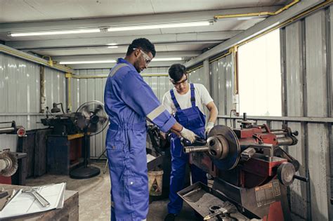 금속 선반 기계를 사용하는 다양성 정비사 또는 금속 세공인은 자동차 수리 차고에서 자동차 디스크 브레이크를 연마합니다 자동차