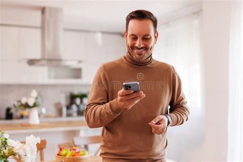 Portrait Of Handsome Entrepreneur Smiling And Using Social Media Apps Over Mobile Phone At Home