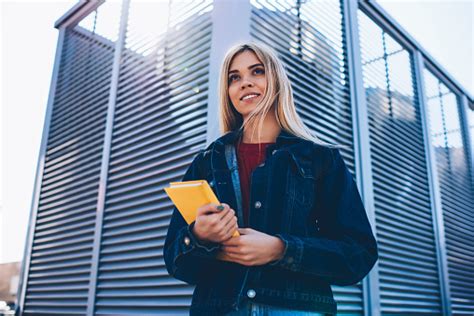 매력적인 미소 금발 여성 블로거 는 손에 메모장을 들고 여름 햇볕이 잘 드는 거리에서 여가 시간을 보내고 봄 도시 환경에서