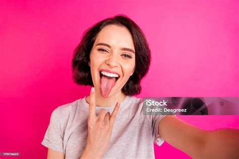 자화상 의 아름다운 매력적인 귀여운 쾌활한 매력적인 매력적인 밀레니얼 록 팬 소녀 점점 그녀의 혀 를 보여주는 그녀의 손가락 뿔