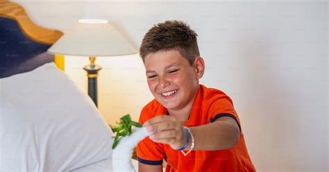 하얀 목욕 수건에서 아름다운 백조를 쳐다보는 아이는 침대에 장식되어 있다 호텔에서 수건 종이 접기 인사를 좋아하는 행복한 아이 사진 Unsplash의 세르비아 이미지