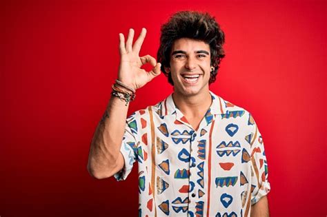 젊은 잘 생긴 남자 휴가 여름 셔츠를 입고 고립 된 빨간 배경 미소 긍정적인 하 고 확인 기호 와 손과 손가락 성공적인 식입니다 긍정적인 감정 표현에 대한 스톡 사진 및