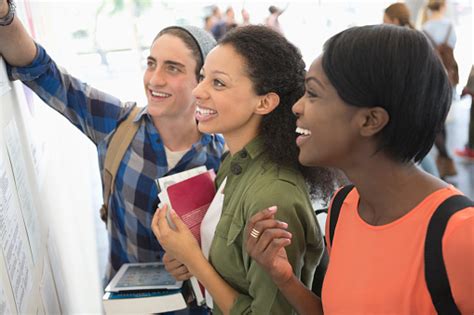 정보 게시판을 보고 책과 디지털 태블릿을 들고 있는 세 명의 웃는 학생 십대 소녀에 대한 스톡 사진 및 기타 이미지 십대 소녀 아프리카 민족 인도 민족 Istock