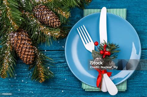 크리스마스 테이블 장소 설정 녹색 냅킨 블루 플레이트 흰색 포크와 칼 겨우살이와 크리스마스 소나무 가지의 장식 된 잔가지와 파란색 테이블 새해 시계 기호입니다 0명에 대한