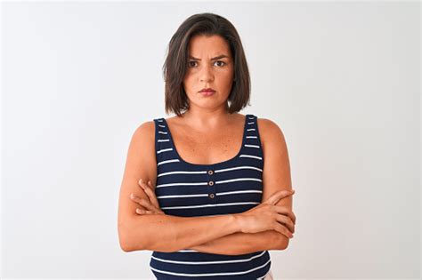 파란색 줄무늬 티셔츠를 입은 젊은 아름다운 여성은 고립 된 흰색 배경 회의론자및 긴장 교차 된 팔로 얼굴에 표정을 거부 위에 서