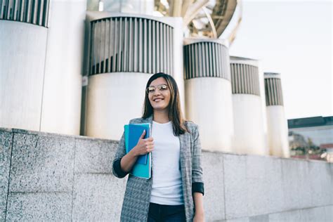 세련된 옷차림과 안경을 입은 여학생의 절반 길이 초상화 도시의 건축물이있는 광장에 책이 서있는 아름다운 백인 힙스터 소녀 방문 여행 즐기기 20 24세에 대한 스톡 사진 및