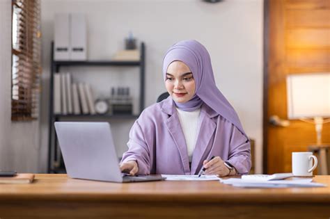 히잡을 쓴 무슬림 사업가의 초상화는 집에서 노트북 컴퓨터로 작업하고 문서 및 청사진 분석을 수행합니다 권한 있는 디지털 기업가 전자 상거래 스타트업 프로젝트 작업 검사