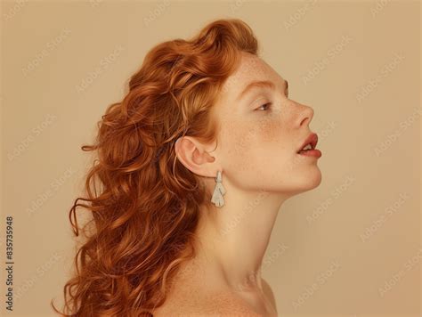 주얼리 룩북 긴 빨간 머리 곱슬 머리를 가진 측면 프로필 백인 모델 어깨는 편안하고 귀는 눈길을 끄는 다이아몬드 귀걸이 베이지 배경 Photos Adobe Stock