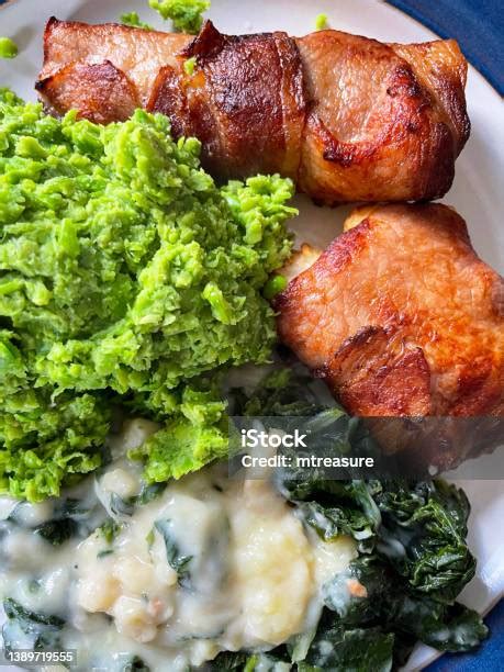 베이컨으로 싸인 구운 대구의 식사 치즈 소스에 버섯 완두콩과 시금치가 들어있는 파란색 테두리 접시의 전체 프레임 이미지 높은 전망 0명에 대한 스톡 사진 및 기타 이미지