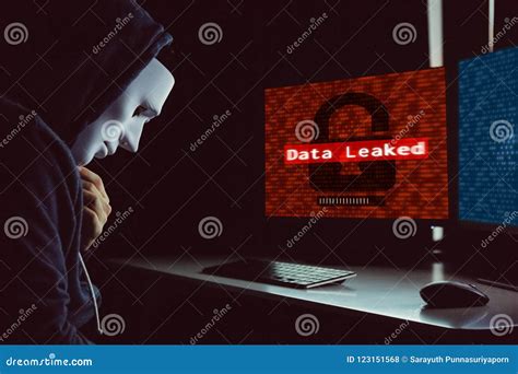 Masked Hacker Under Hood Using Computer To Hack Into System And Employ