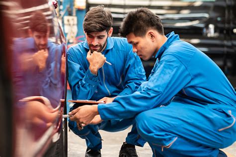 현대 자동차 서비스 상점에서 체크 리스트를 사용하여 자동차 타이어와 휠을 검사하는 두 명의 전문 적인 모습 기술자 자동차 비즈니스 또는 자동차 수리 개념 2명에 대한 스톡