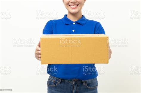고립 된 흰색 배경에 소포 판지 상자를 들고 서있는 파란색 유니폼을 입은 행복한 배달 아시아 여성 웃는 여성 배달 상자 패키지