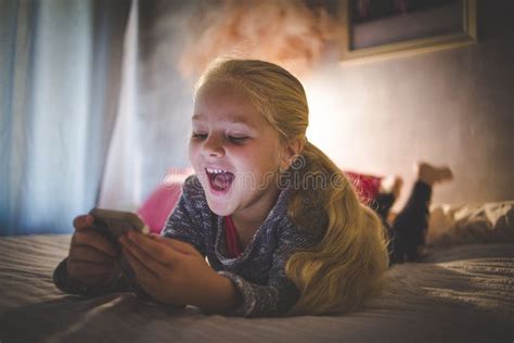 Excited Blonde Haired Girl Laying On Her Bed Watching Videos On A